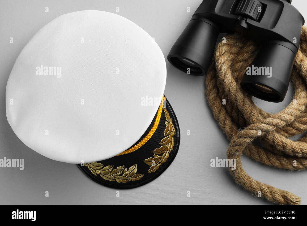 Peaked cap, rope and binoculars on light grey background, flat lay ...