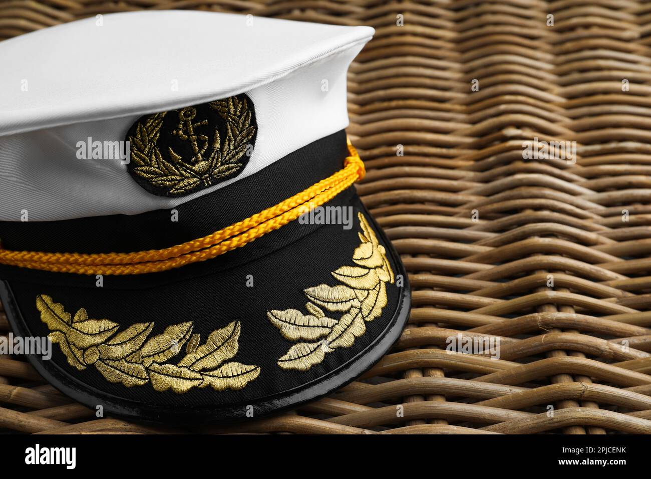 Peaked cap with accessories on wicker surface, closeup. Space for text ...