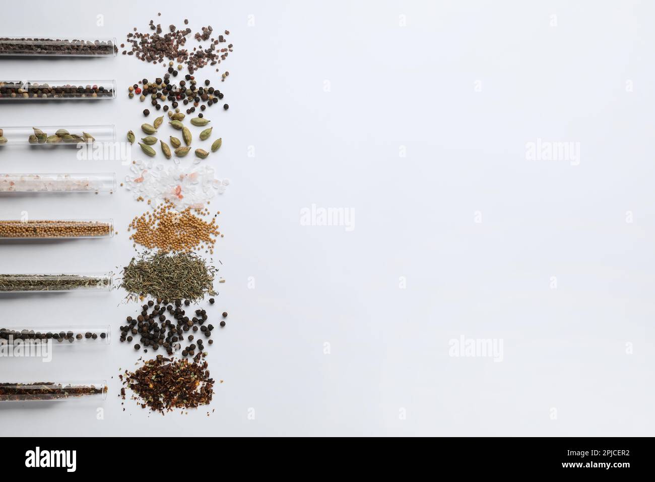 Test tubes with various spices on white background, flat lay. Space for ...