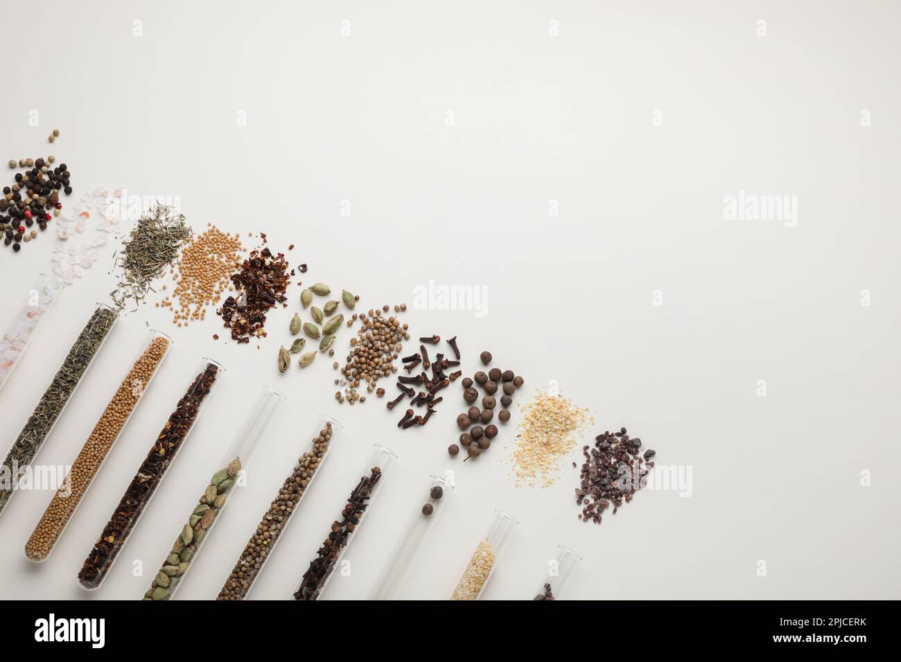 Test tubes with various spices on white background, flat lay. Space for ...