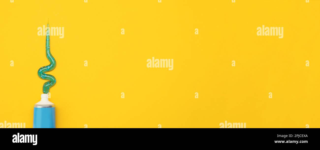 Tube with squeezed out toothpaste on yellow background, top view with ...