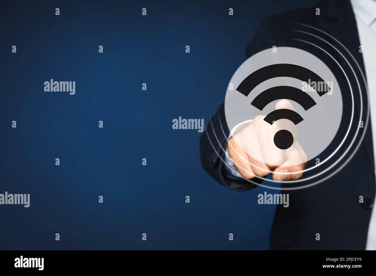 Man touching Wi Fi symbol on digital screen against dark blue ...