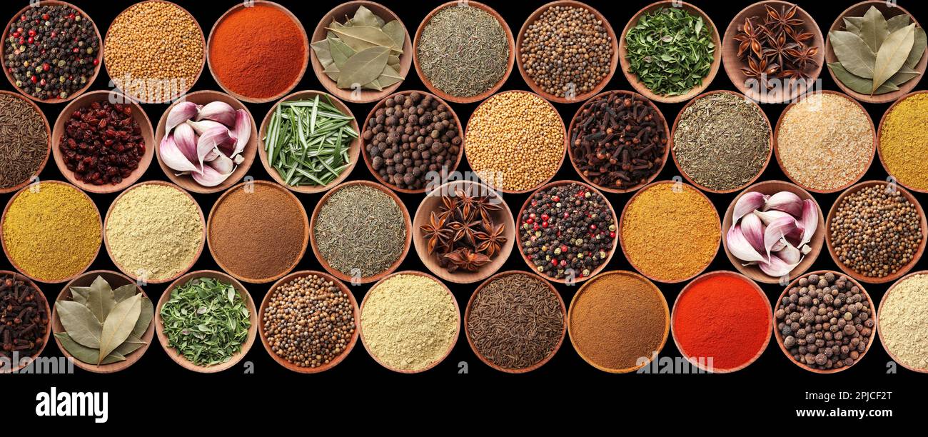 Collection of different aromatic spices and herbs on black background ...