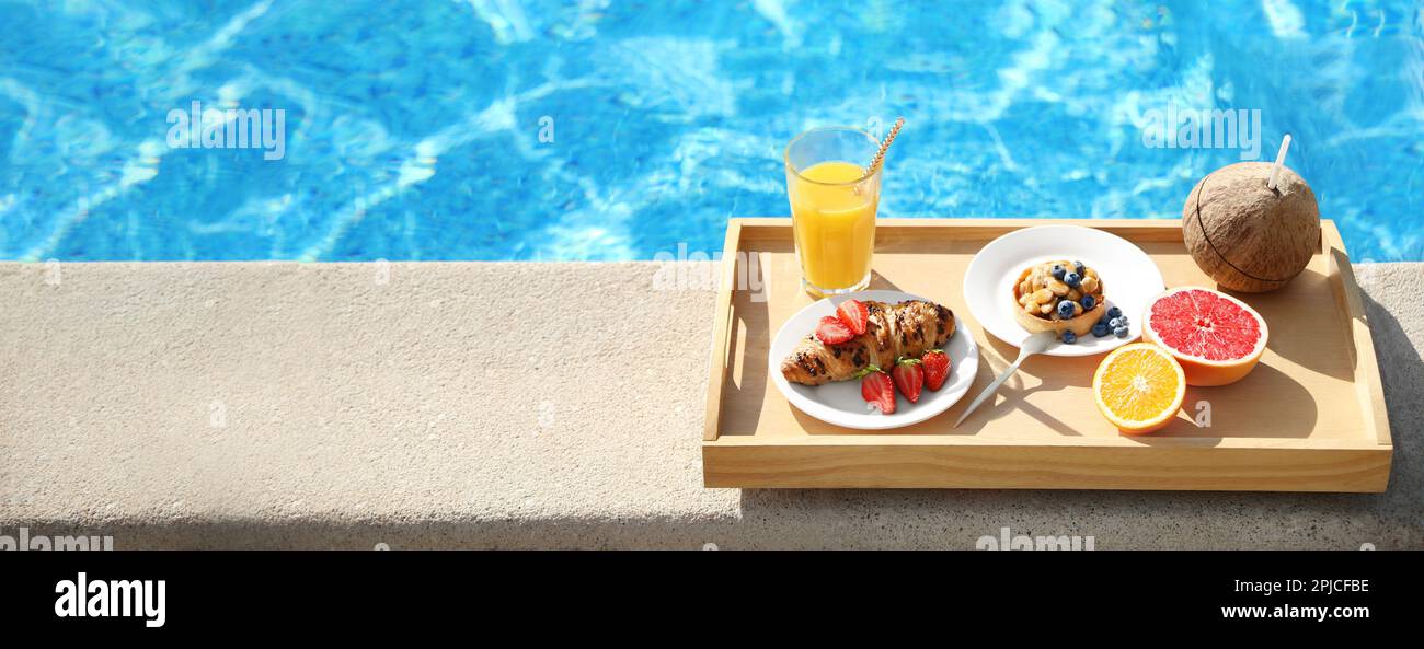 Tray with delicious breakfast near swimming pool, space for text ...