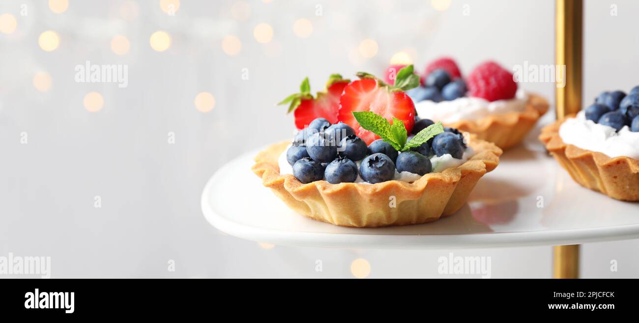 Tarts with different berries on cake stand, space for text. Banner ...