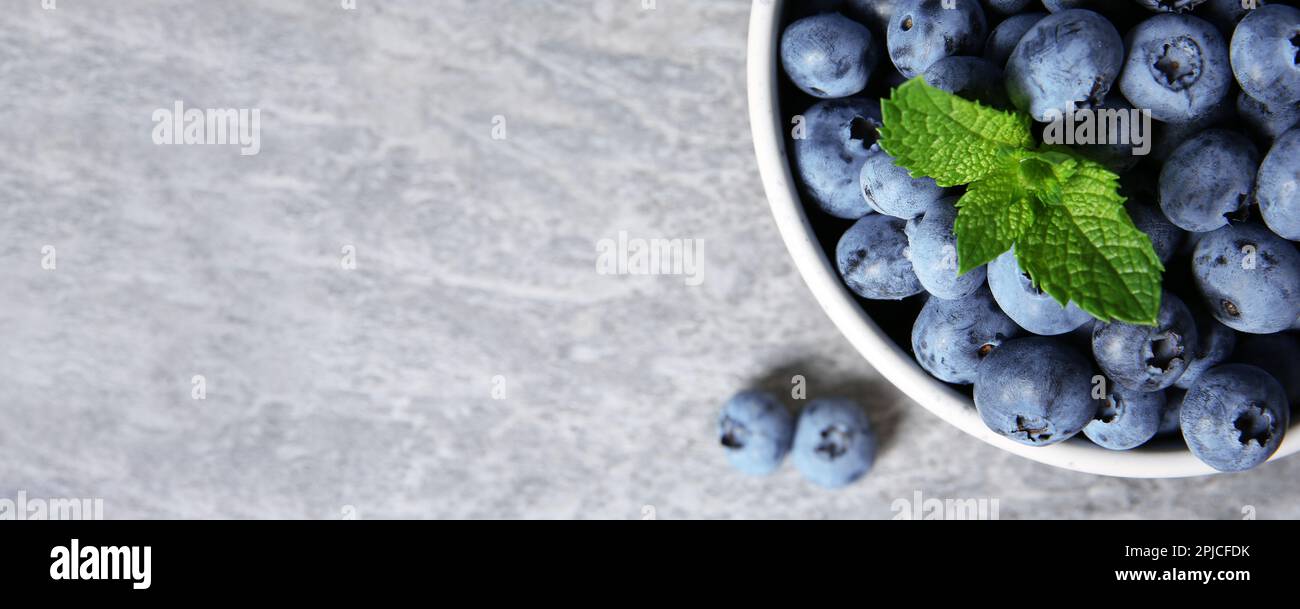 Tasty fresh blueberries on grey table, top view with space for text ...