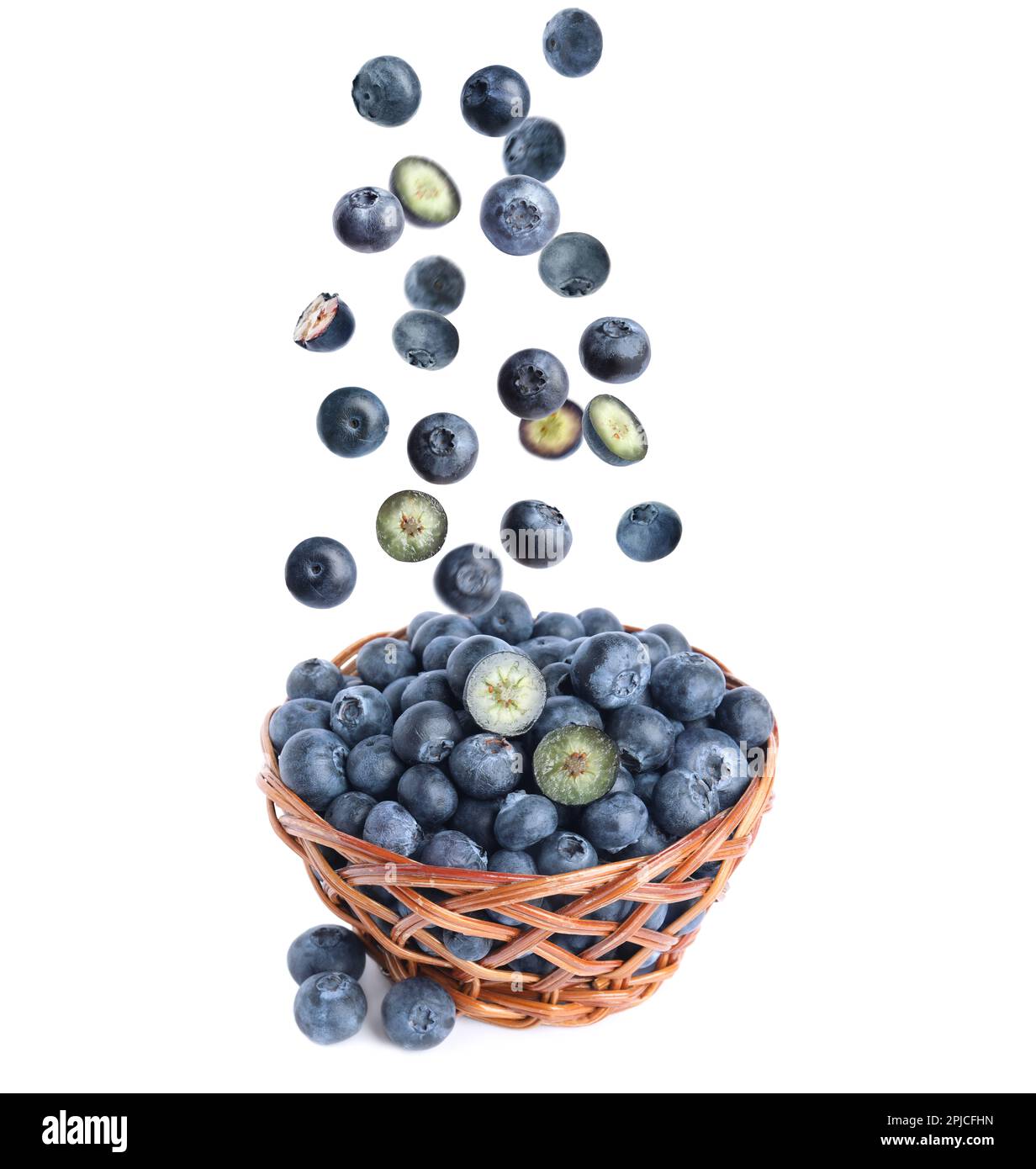 Fresh ripe blueberries falling into wicker bowl on white background ...