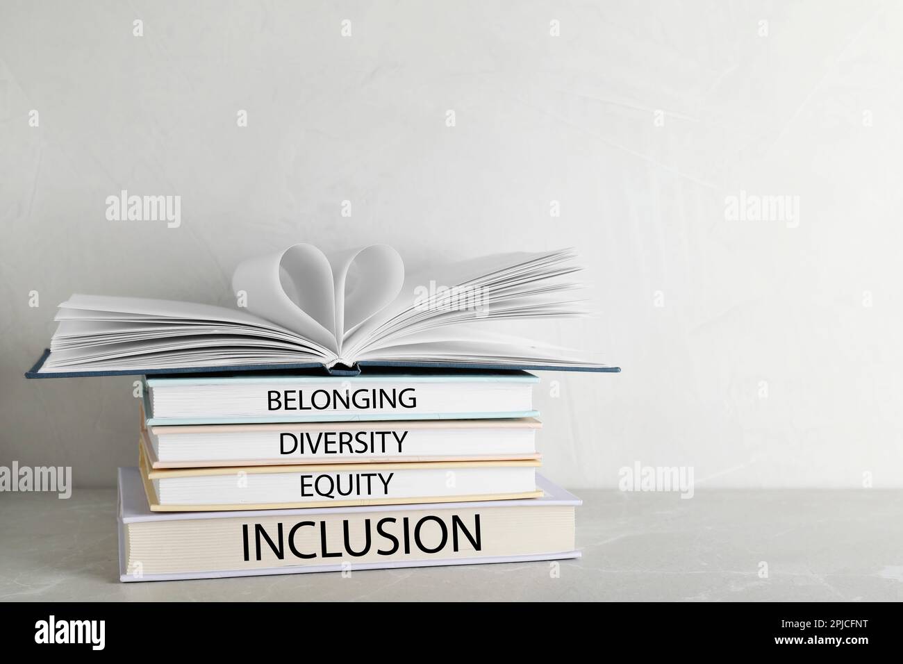 Stack of hardcover books with words Belonging, Diversity, Equity ...