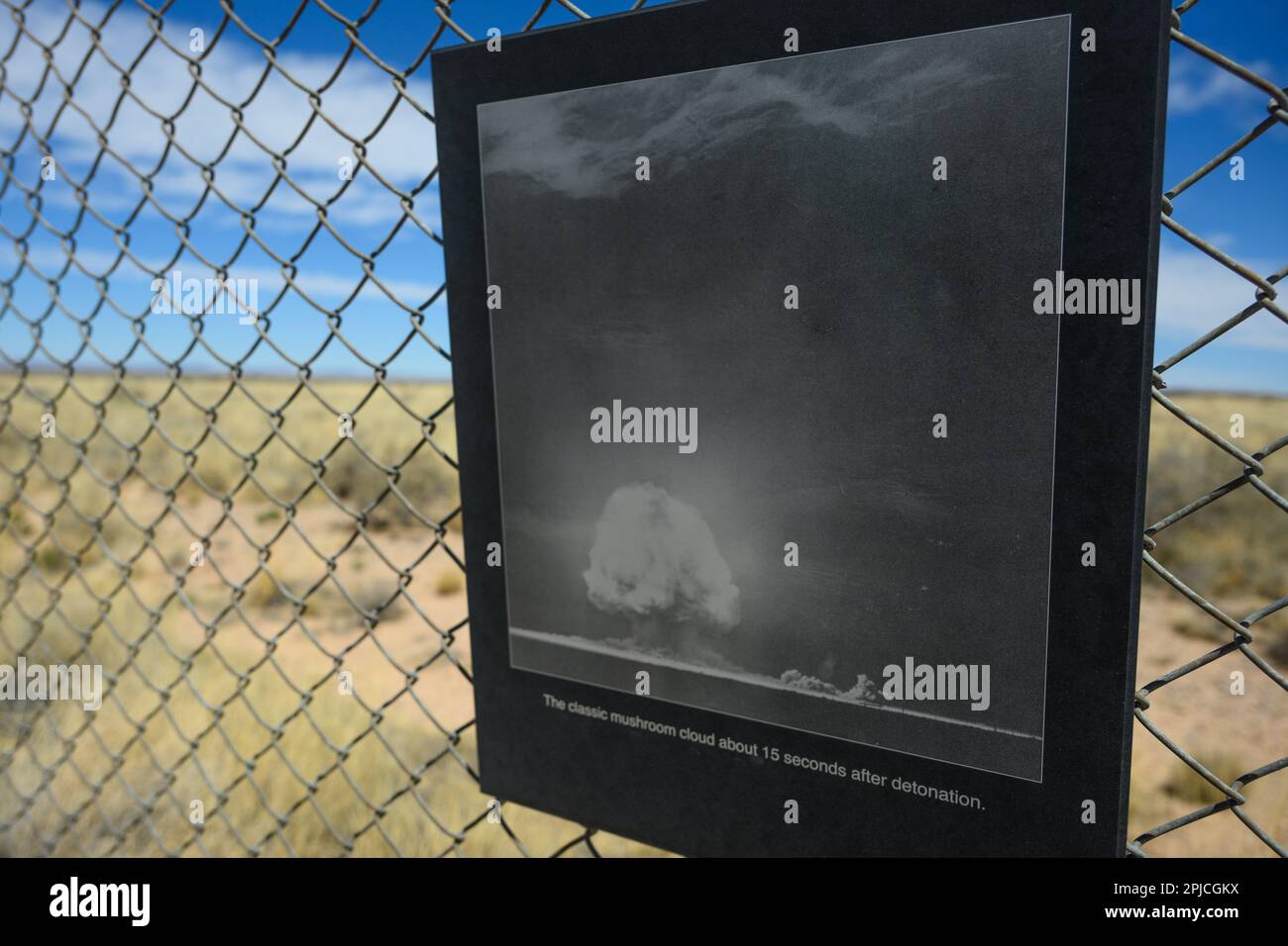 A photograph of the first atomic bomb test is hung on a fence at the ...