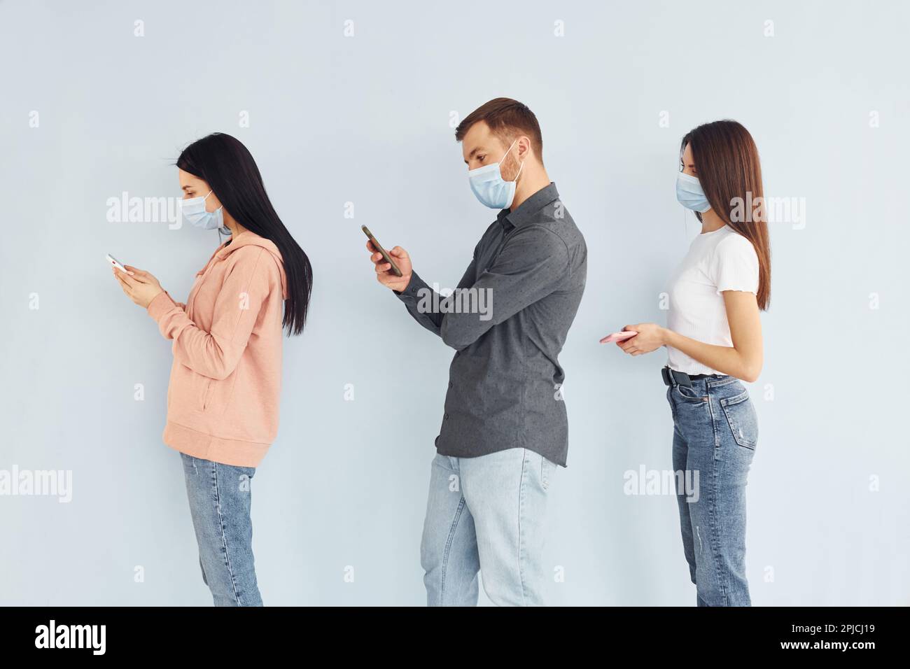 Three people standing together in the studio against white background ...