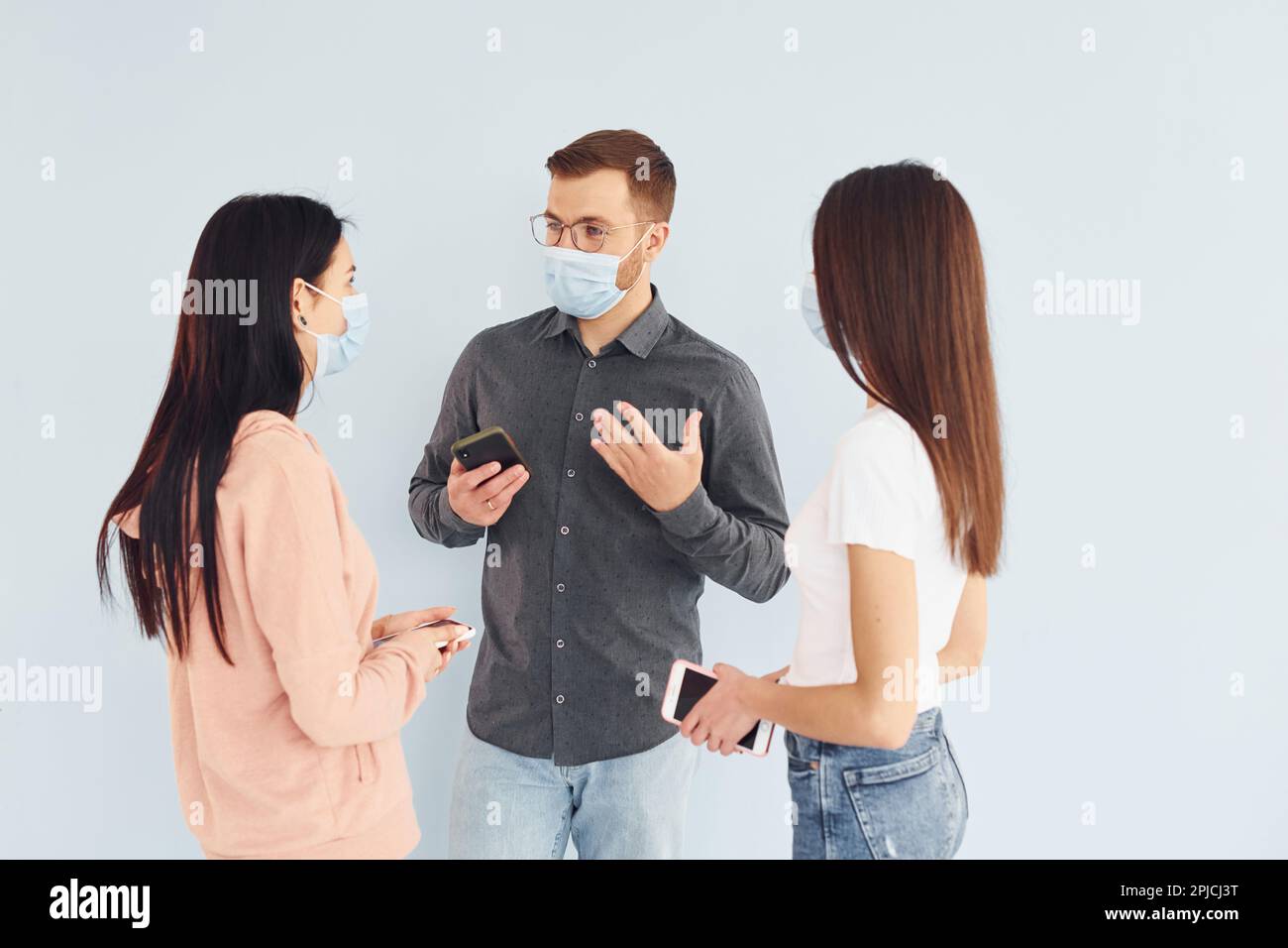 Three people standing together in the studio against white background ...