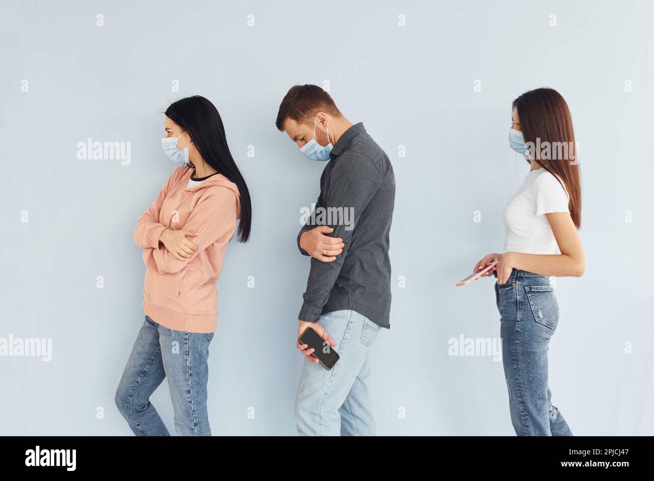 Three people standing together in the studio against white background ...