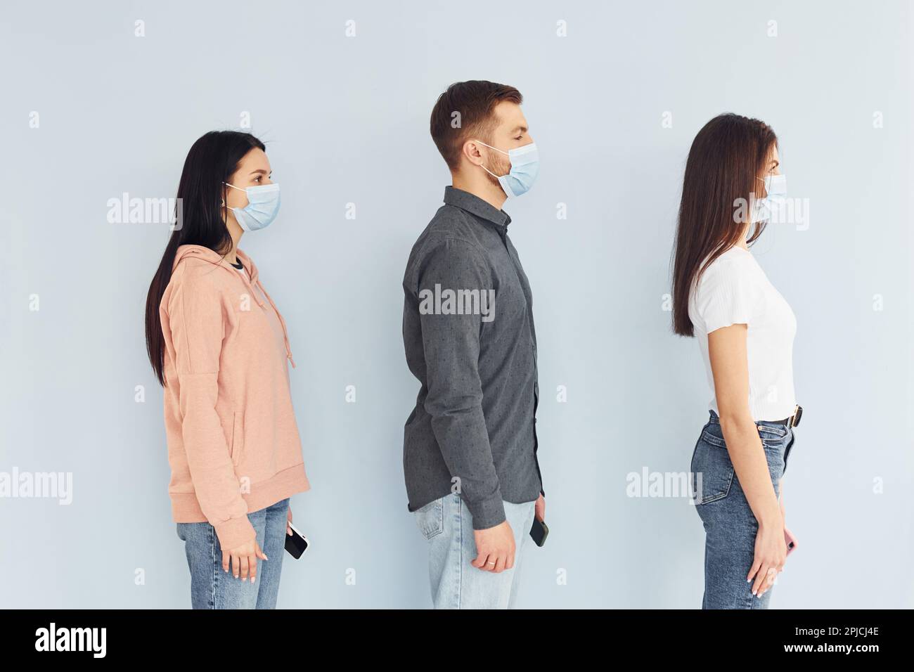 Three people standing together in the studio against white background ...