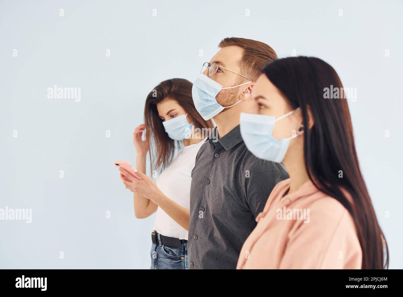 Three people standing together in the studio against white background ...