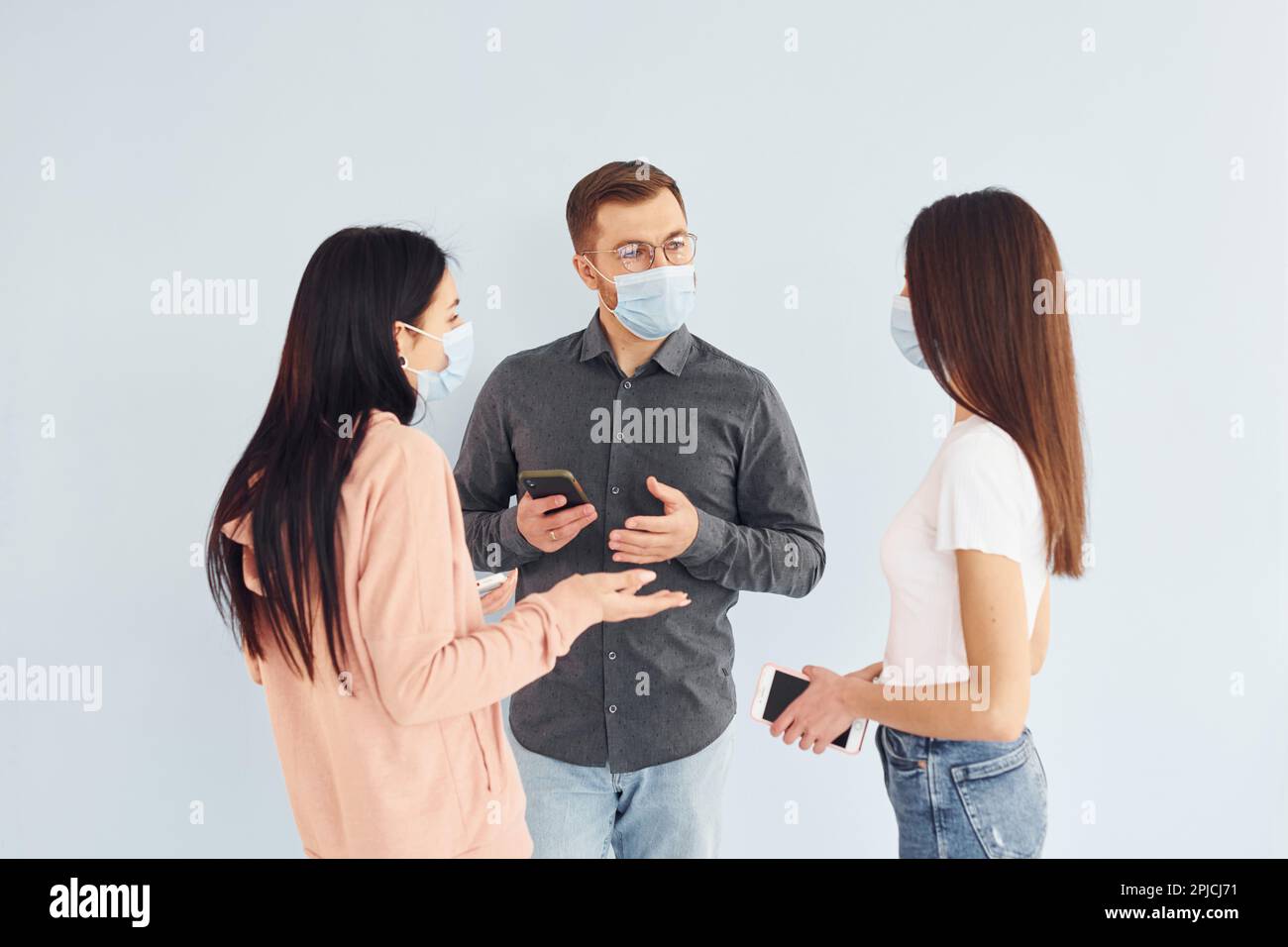 Three people standing together in the studio against white background ...