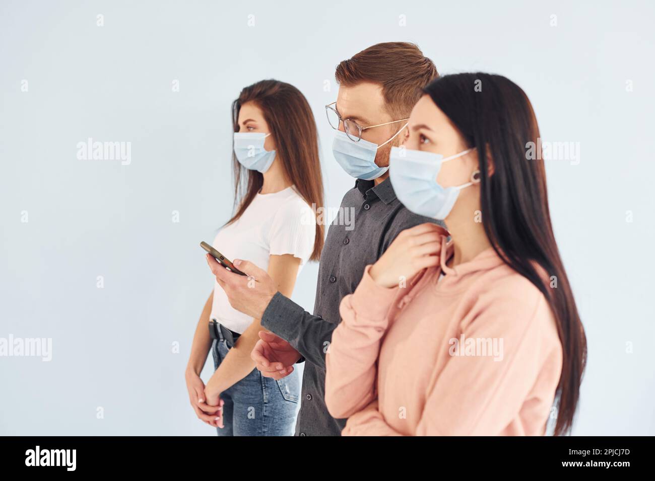 Three people standing together in the studio against white background ...