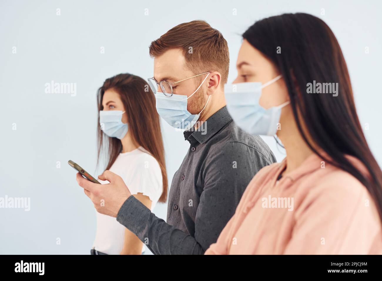 Three people standing together in the studio against white background ...