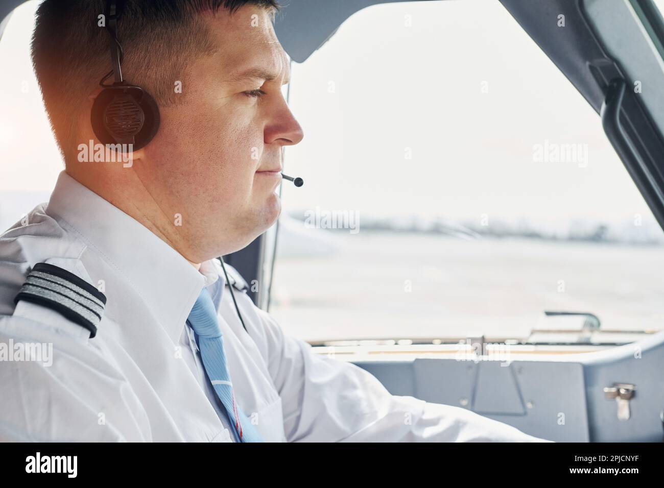 Side view. Pilot in formal wear sits in the cockpit and controls ...
