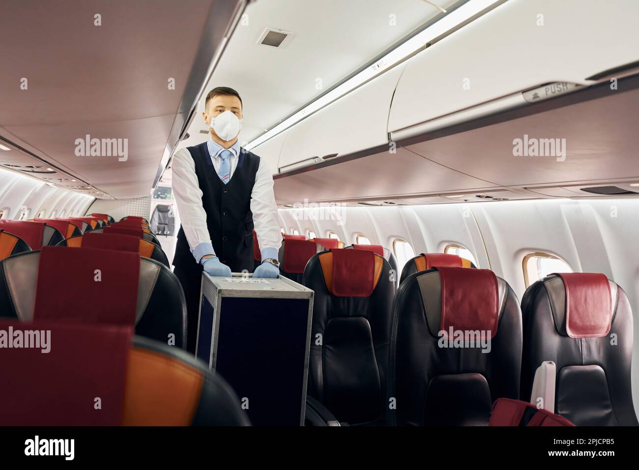 Steward in uniform is walks with luggage inside of airplane Stock Photo ...