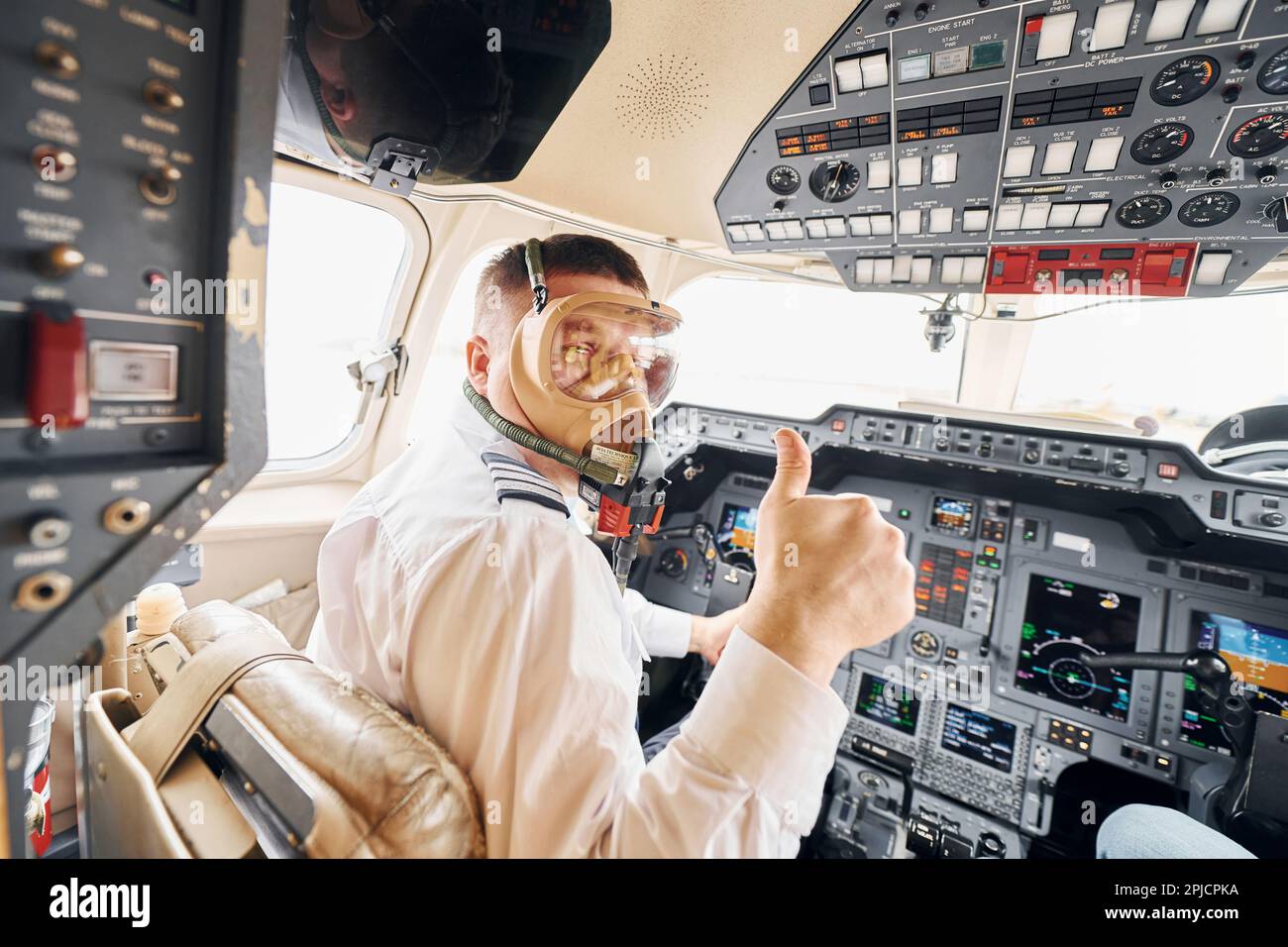 In oxygen mask. Pilot in formal wear sits in the cockpit and controls ...