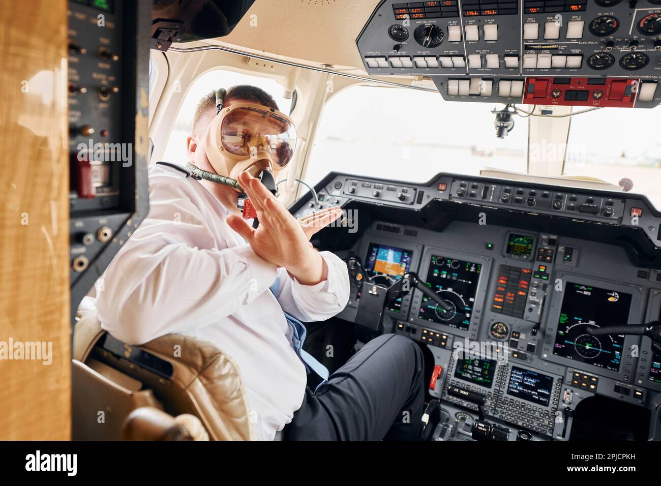 In oxygen mask. Pilot in formal wear sits in the cockpit and controls ...