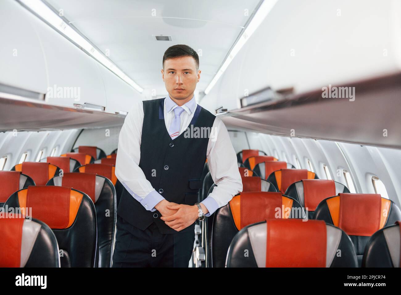 Young steward in uniform on the work in the passanger airplane Stock ...