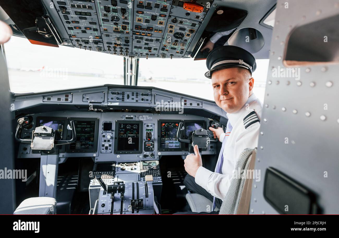 Looks behind. Pilot on the work in the passenger airplane. Preparing ...