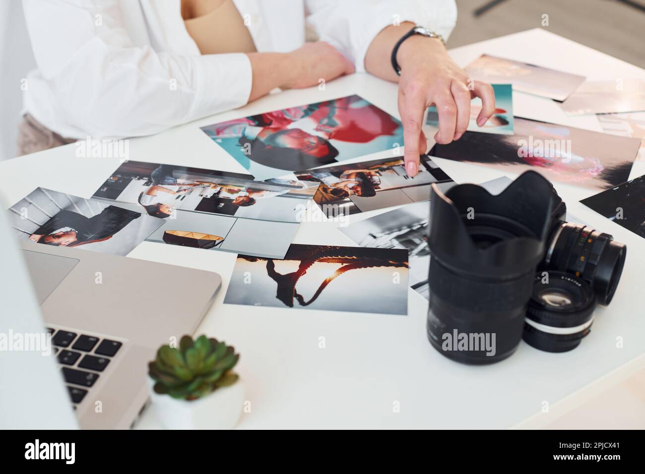 Close up view of table with camera and photos. Female photographer at ...