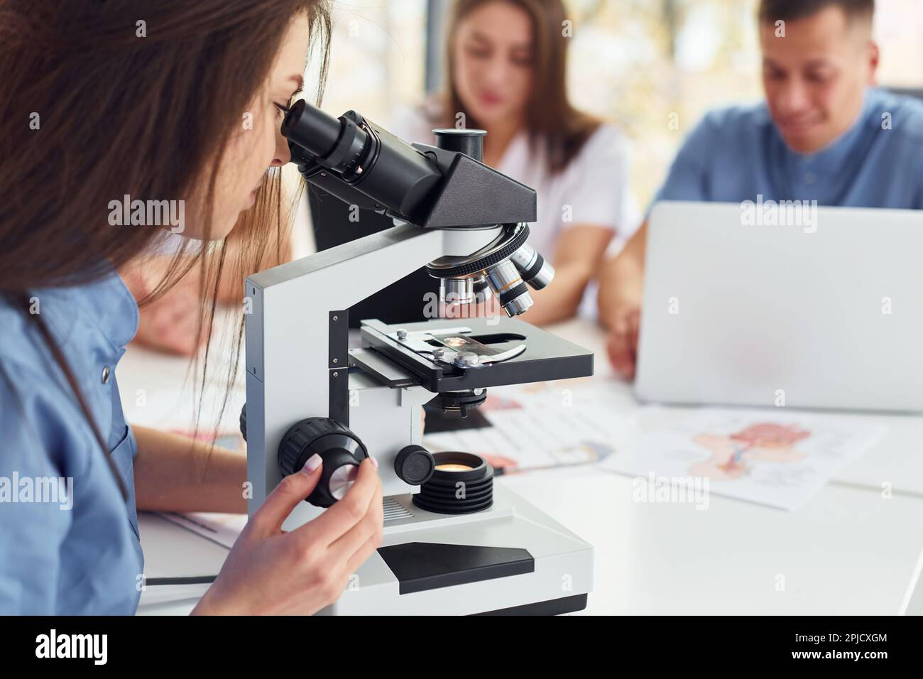 Using microscope. Group of young doctors is working together in the ...