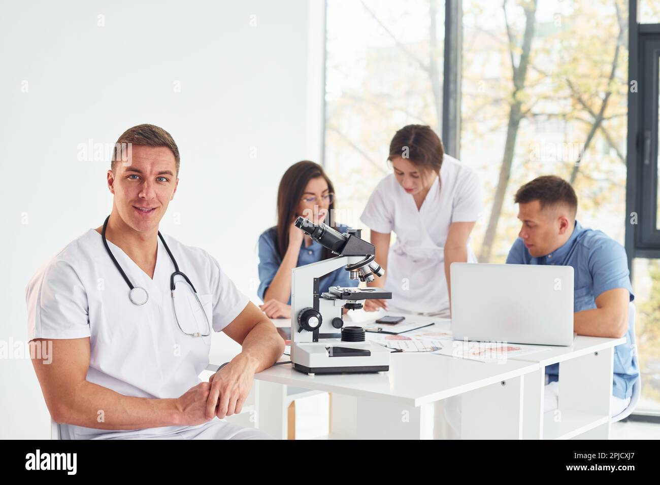 Using microscope. Group of young doctors is working together in the ...