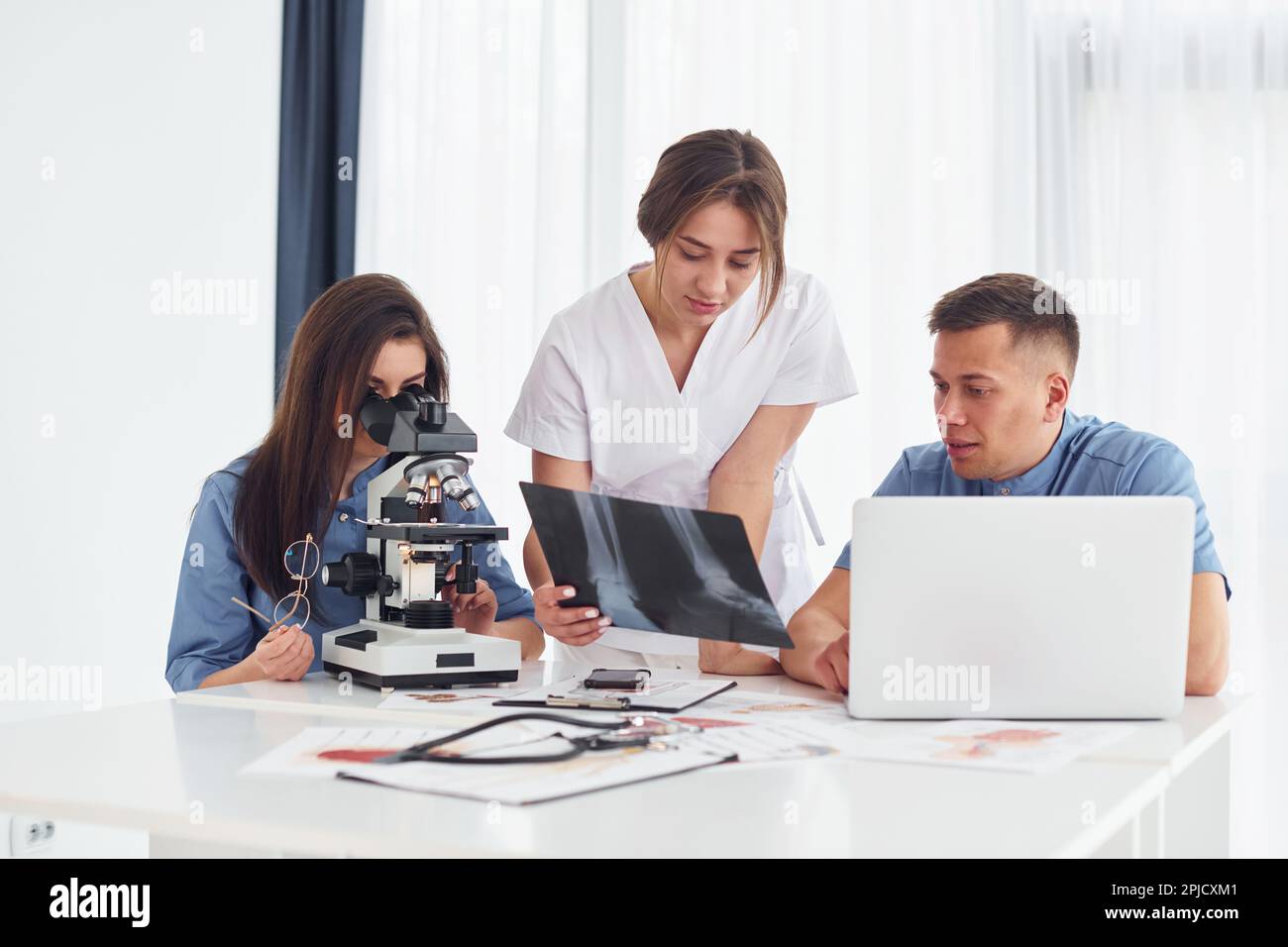 Using microscope. Group of young doctors is working together in the ...
