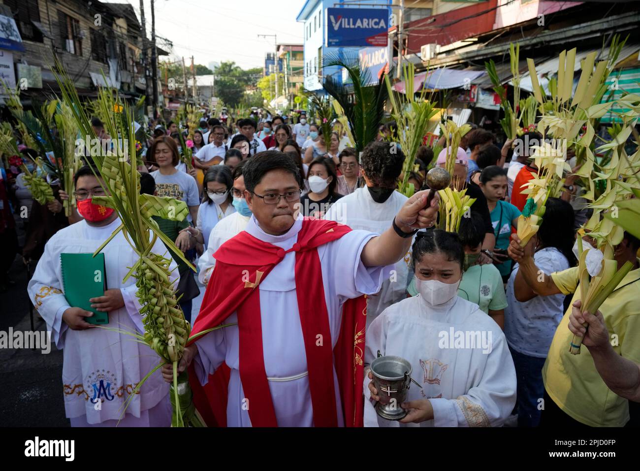 A Roman Catholic priest blesses palm fronds with holy water to ...