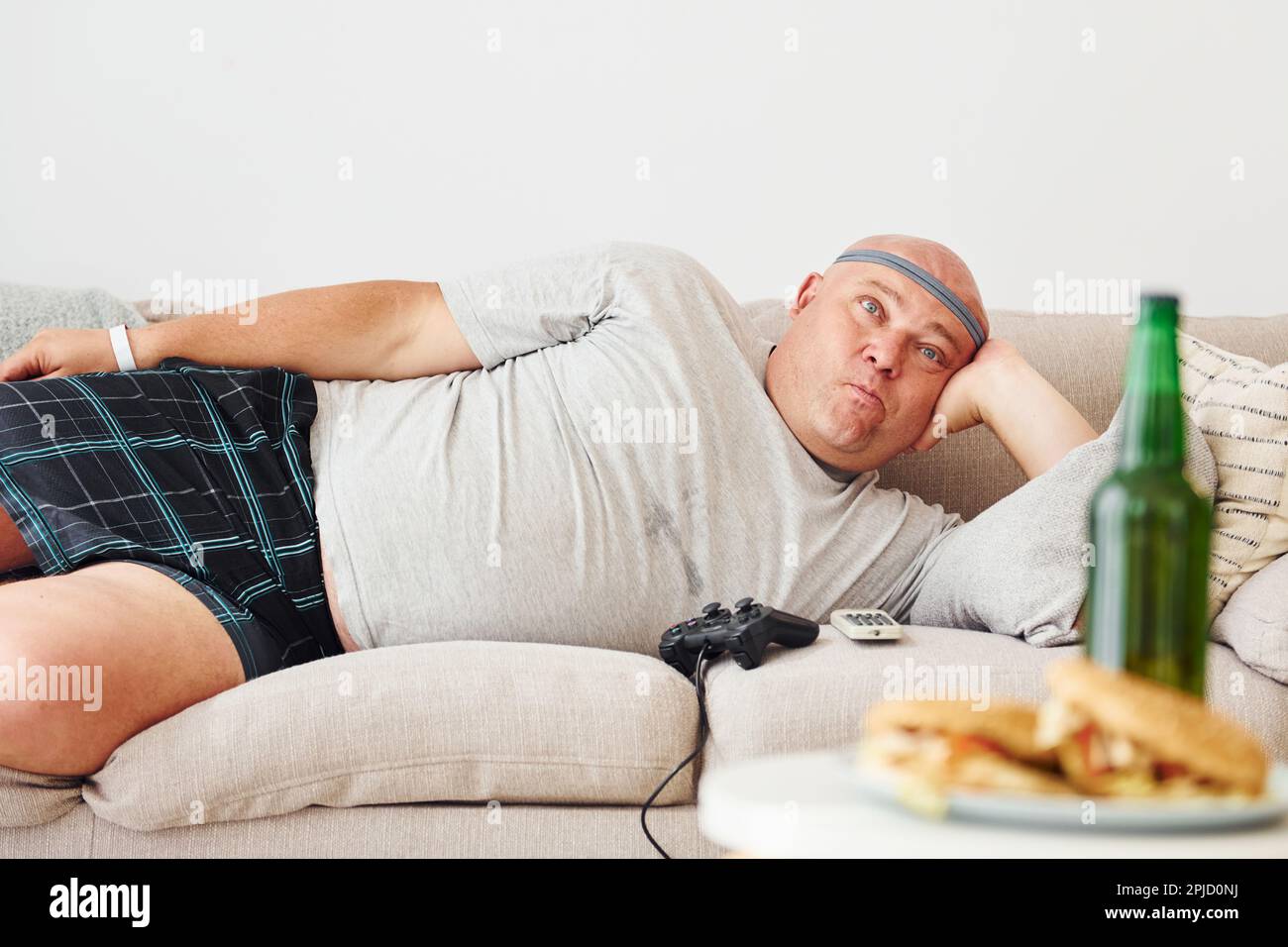Hamburgers and beer. Man lying on the sofa. Funny overweight man in ...