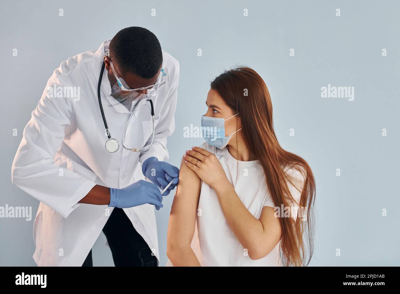 Young african american doctor giving injection to woman at hospital ...