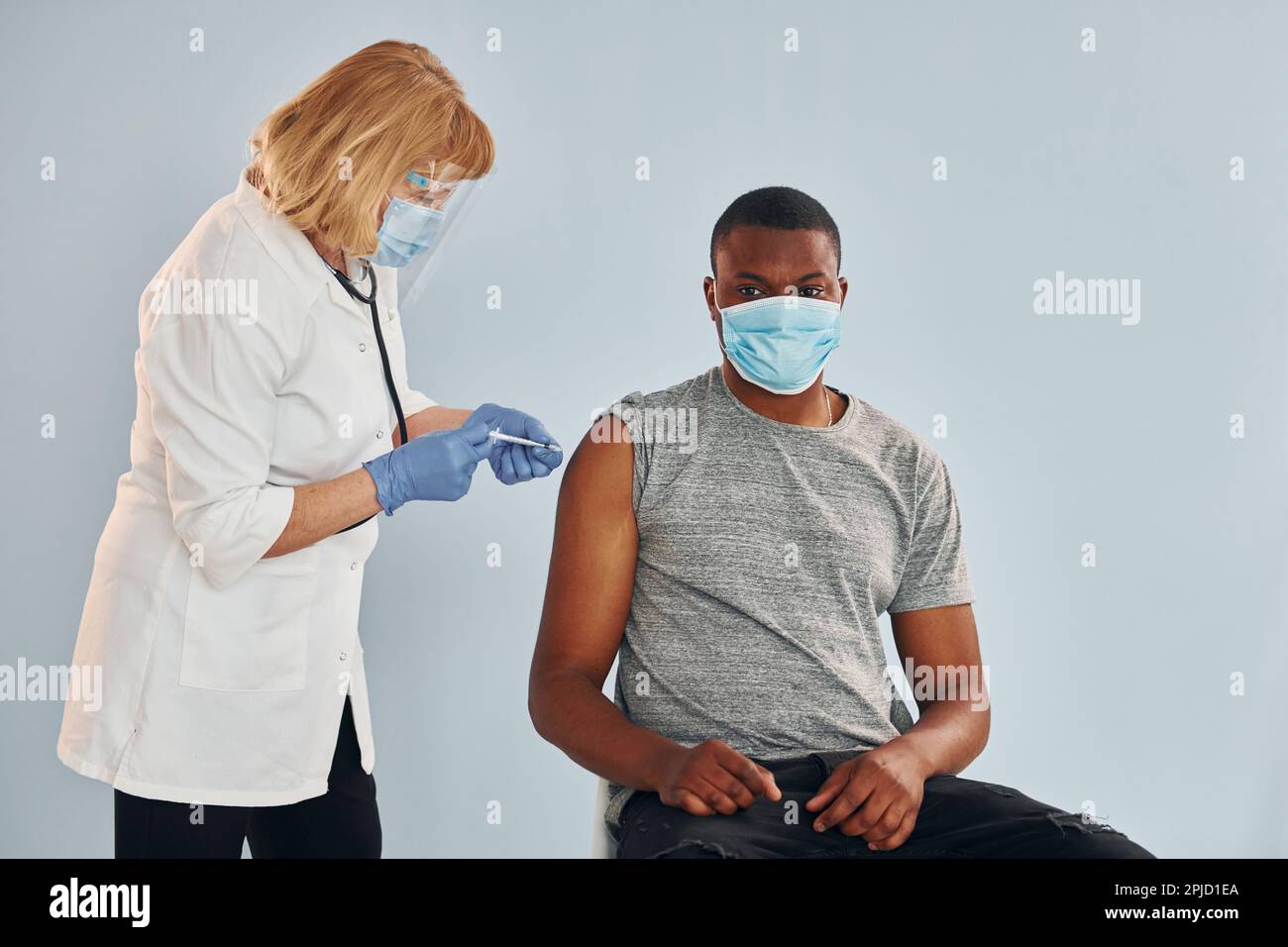 Senior doctor giving injection to young african american man at ...