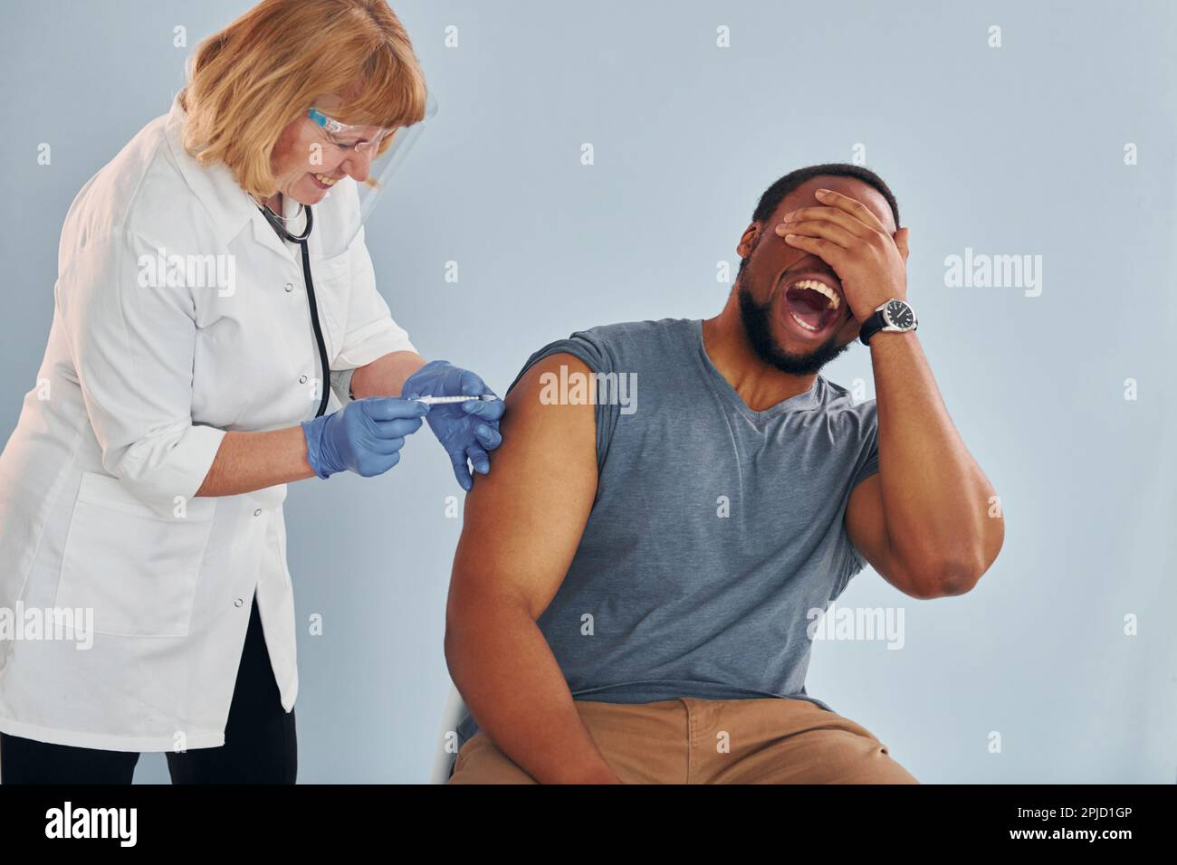 Senior doctor giving injection to young african american man at ...