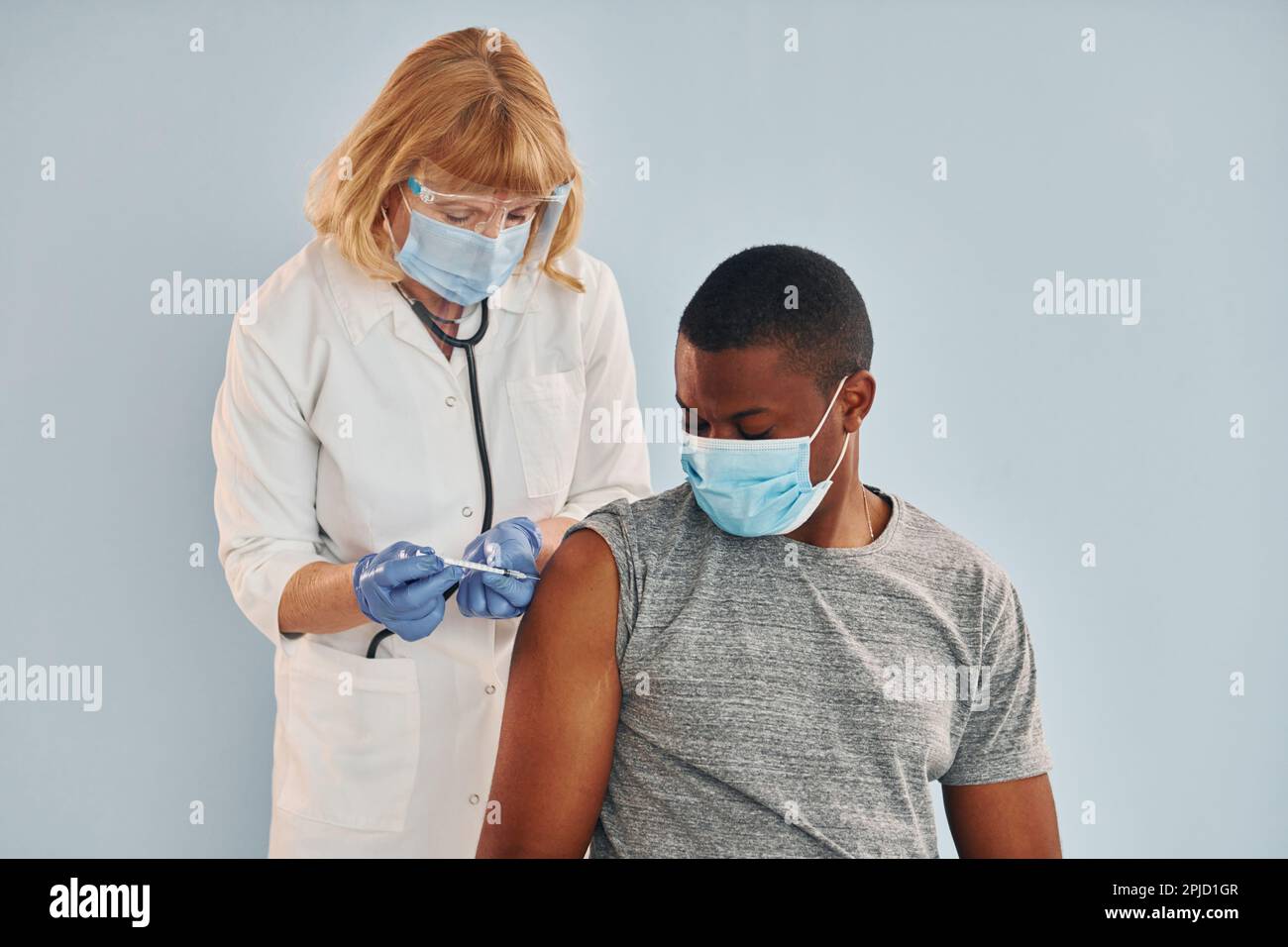 Senior doctor giving injection to young african american man at ...