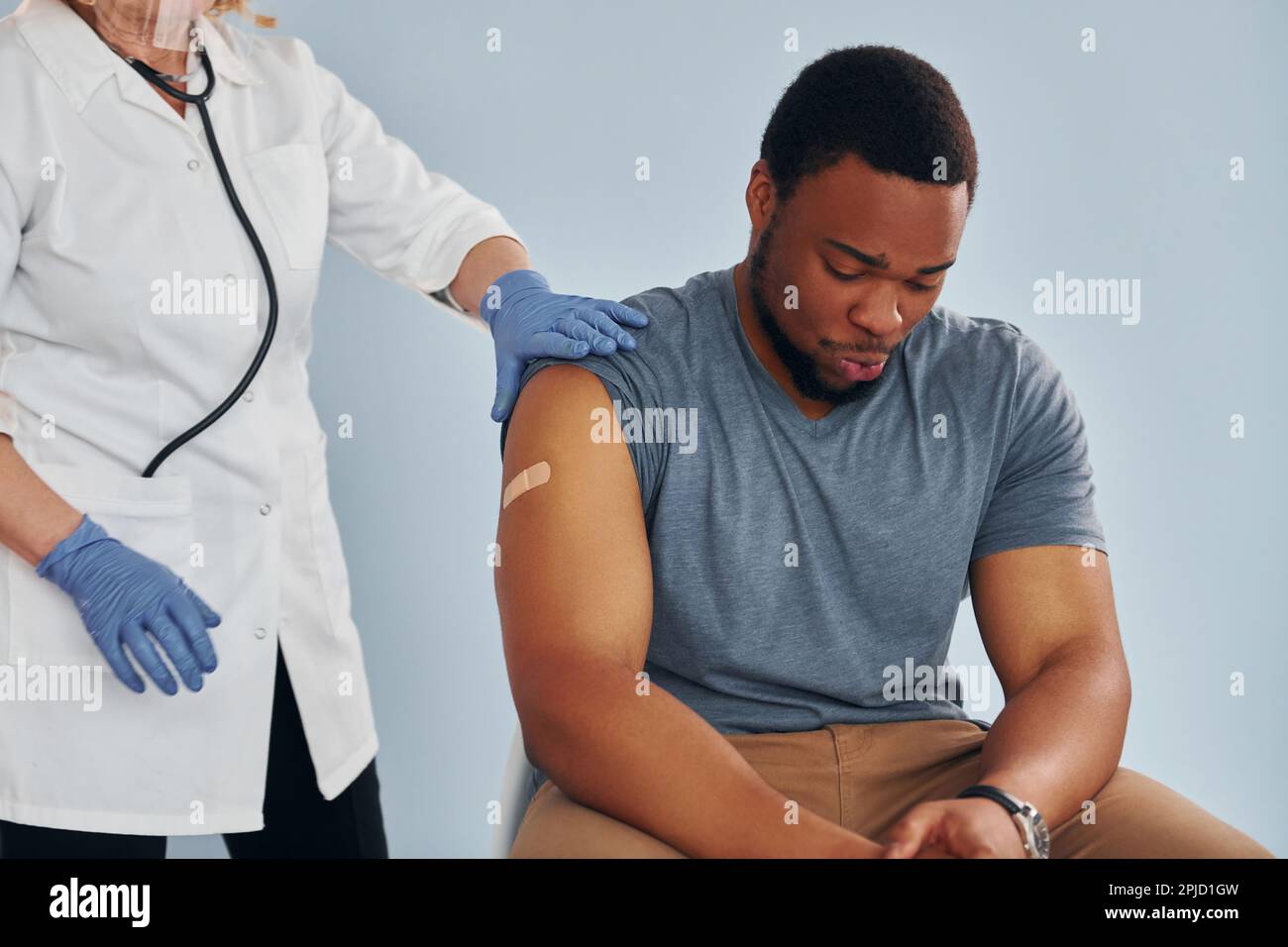 Senior doctor giving injection to young african american man at ...