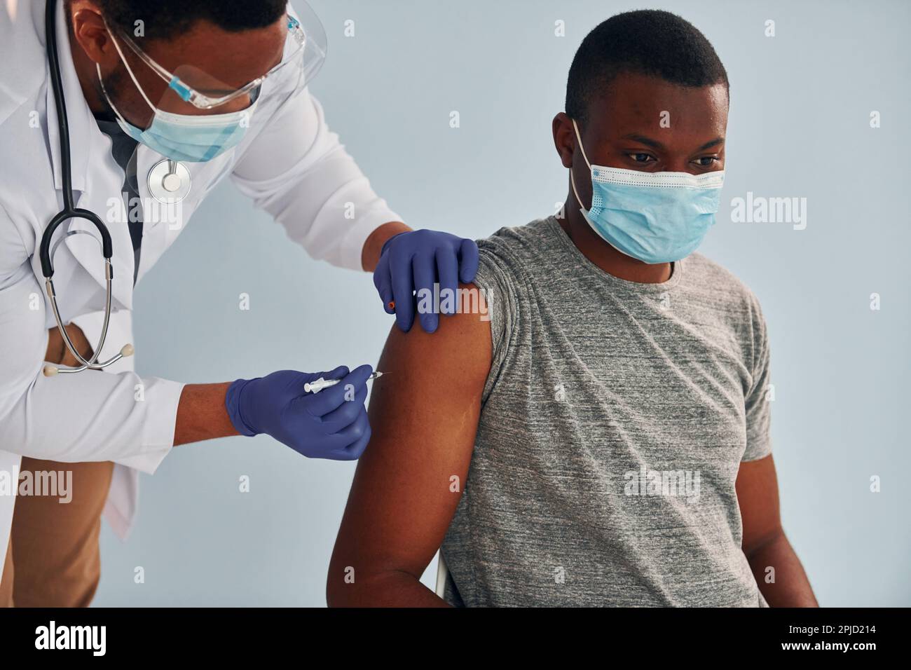 Professional young african american doctor giving injection to patient ...
