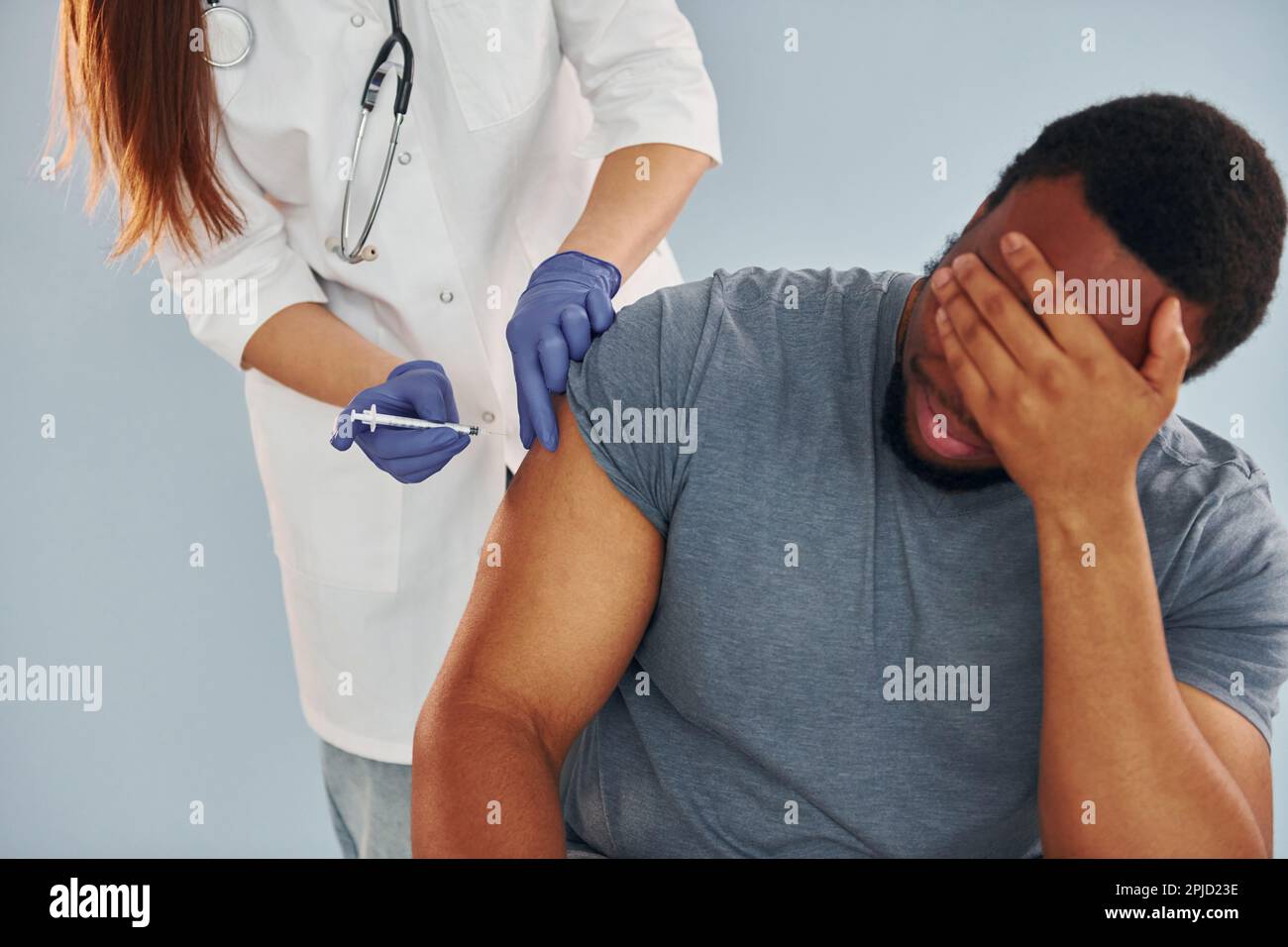 Female doctor giving injection to african american man at hospital ...