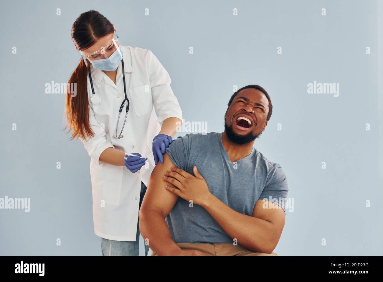 Female doctor giving injection to african american man at hospital ...