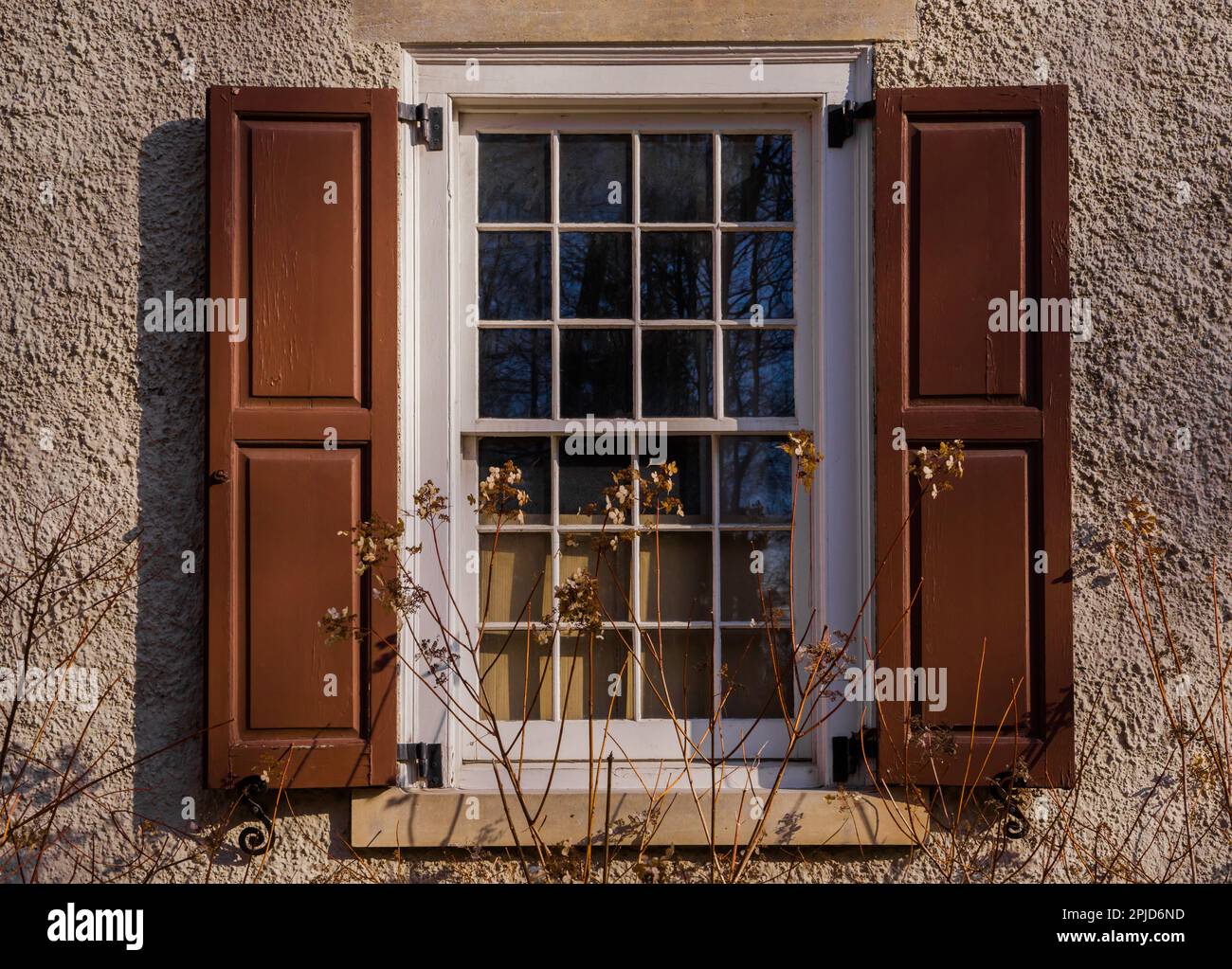 Window with wooden shutters and flowers in front of a stone wall ...