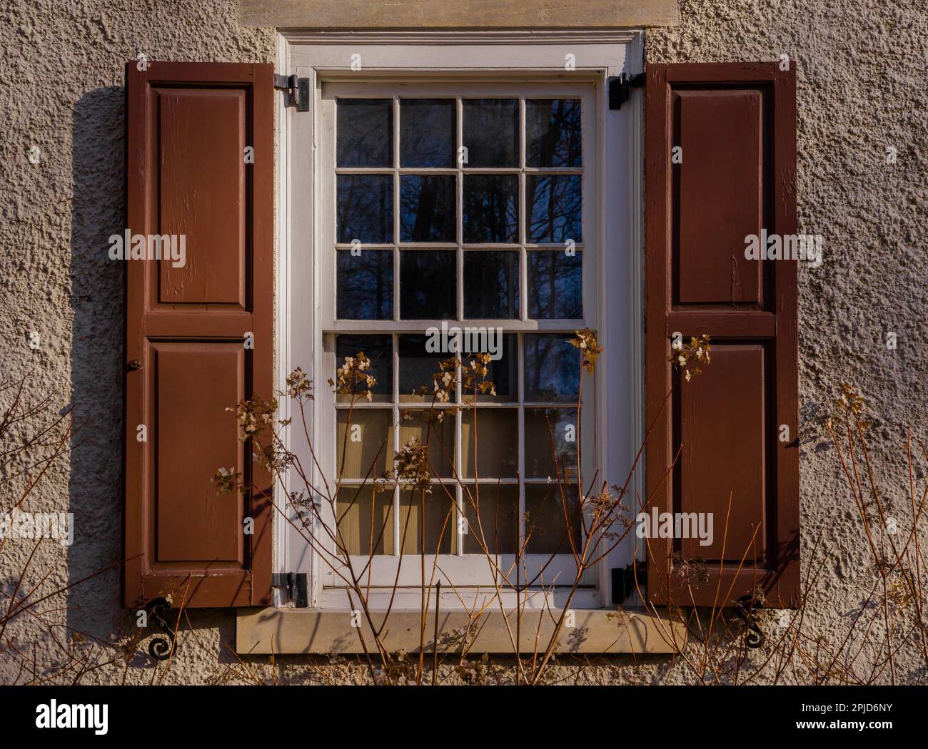 Window with wooden shutters and flowers in front of a stone wall ...