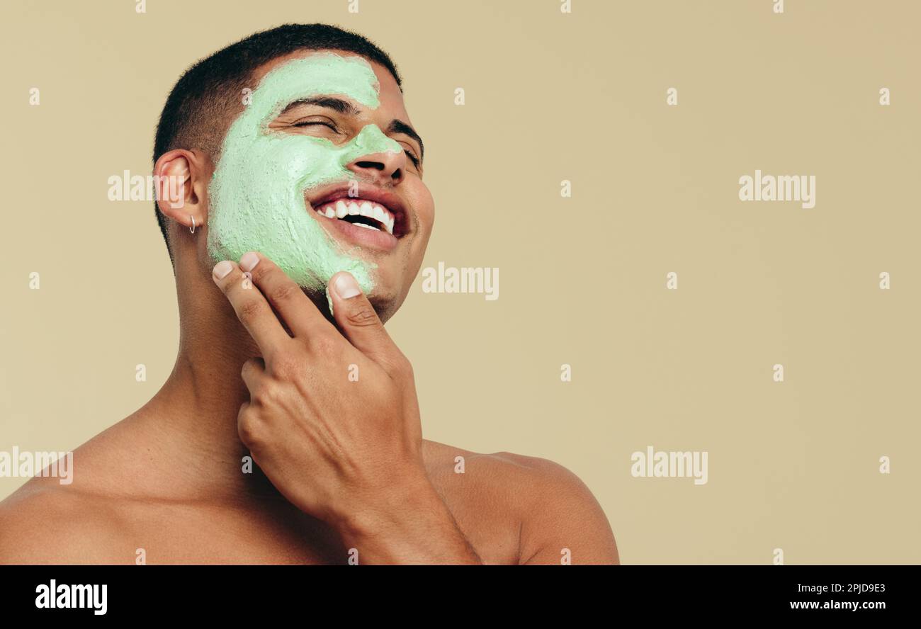 Happy young man pampering his skin with a face mask, the perfect way to ...