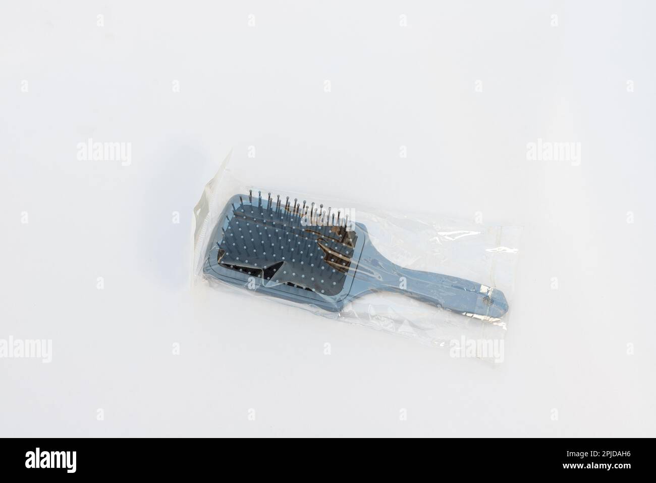 Hair brush in a plastic packing on white isolated background Top view ...