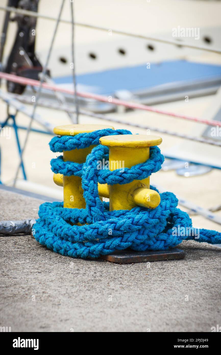 Thick blue rope and yellow bollards on wharf using for anchorage of ...