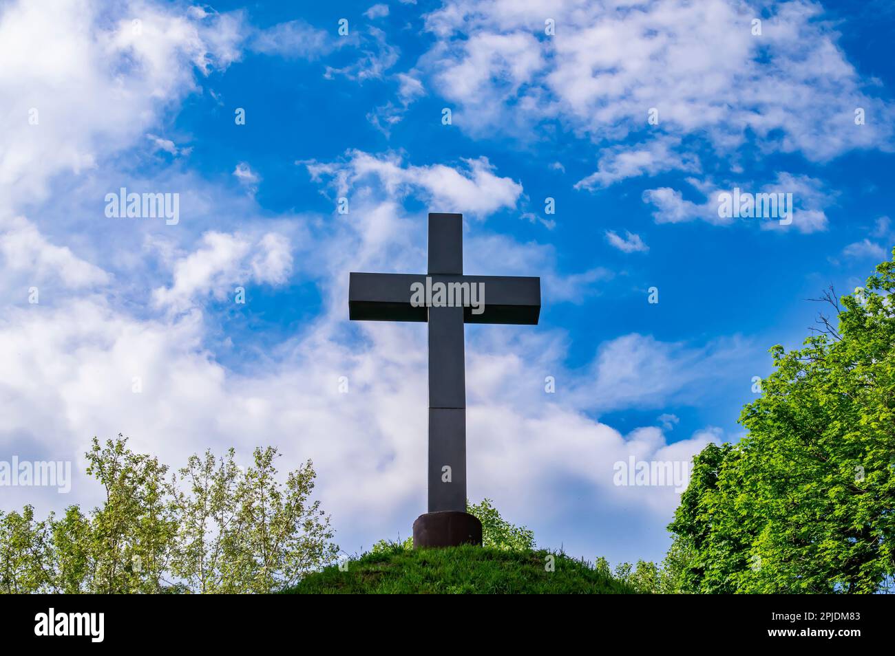 Christian cross on a mound against a blue sky with white clouds ...