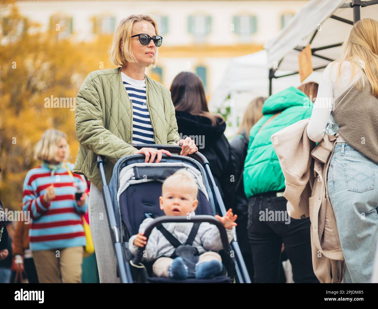 Mother waling and pushing his infant baby boy child in stroller in ...