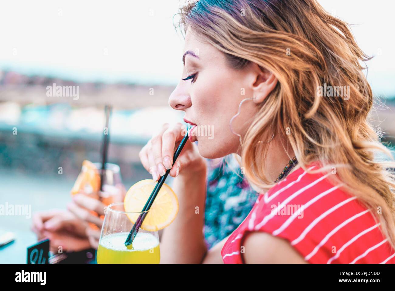 Close-up profile of young Caucasian woman sipping a green cocktail ...