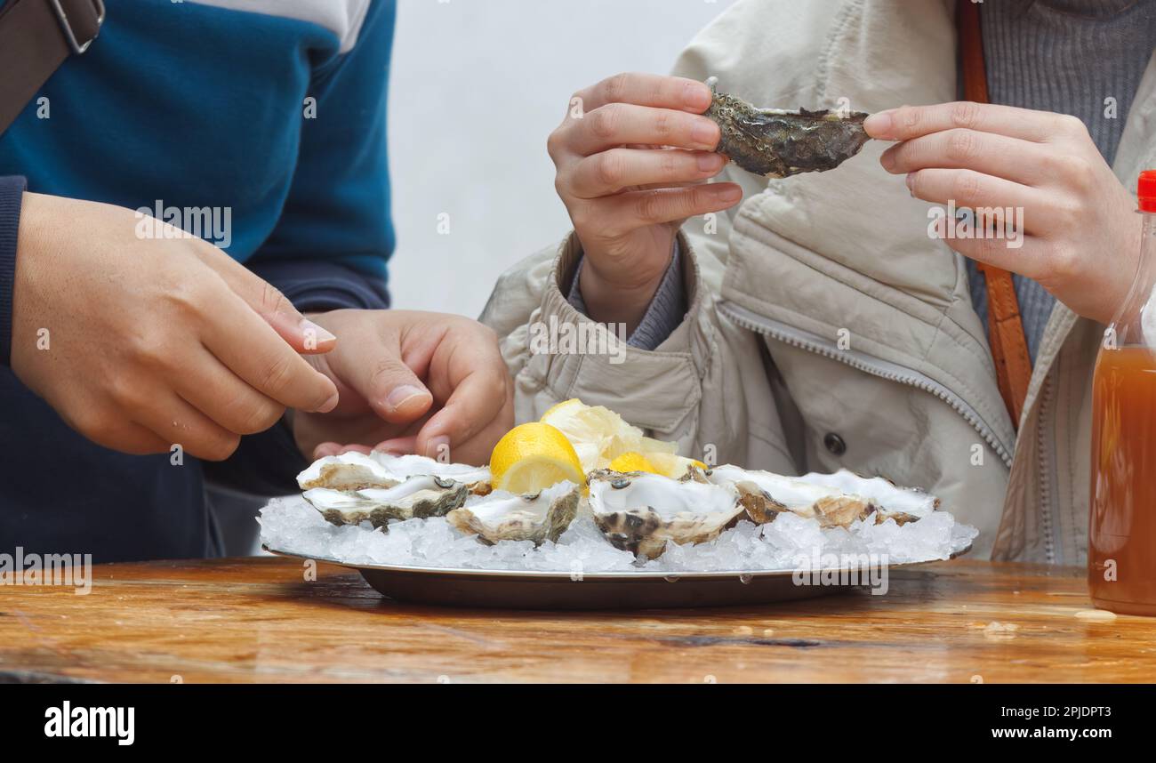 Eating oysters at a street food market, womens hands holding an oyster ...